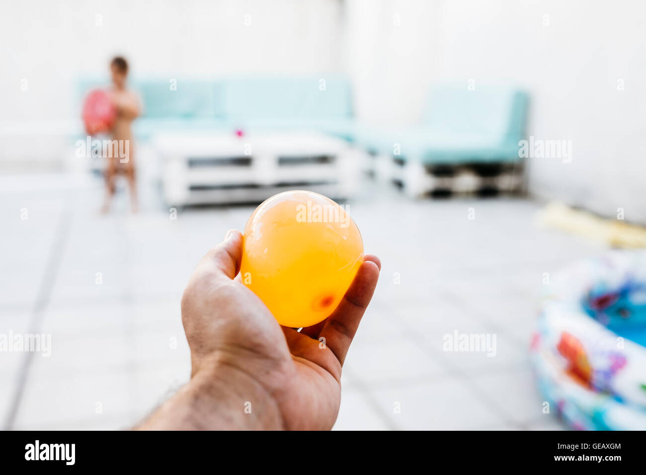 Man's hand holding yellow waterballoon Stock Photo - Alamy