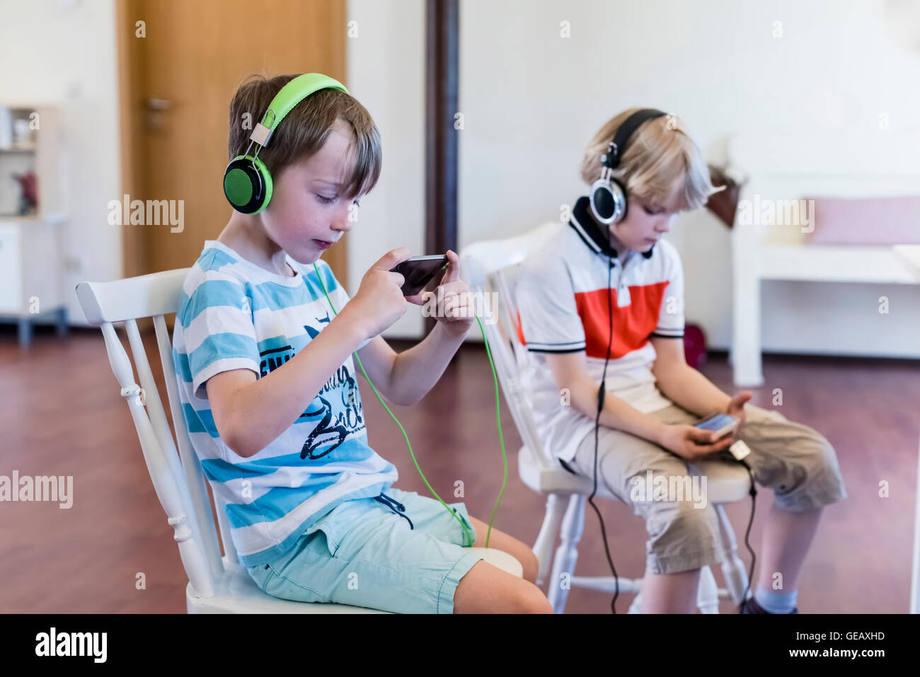 Two boys with cell phones and headphones Stock Photo - Alamy