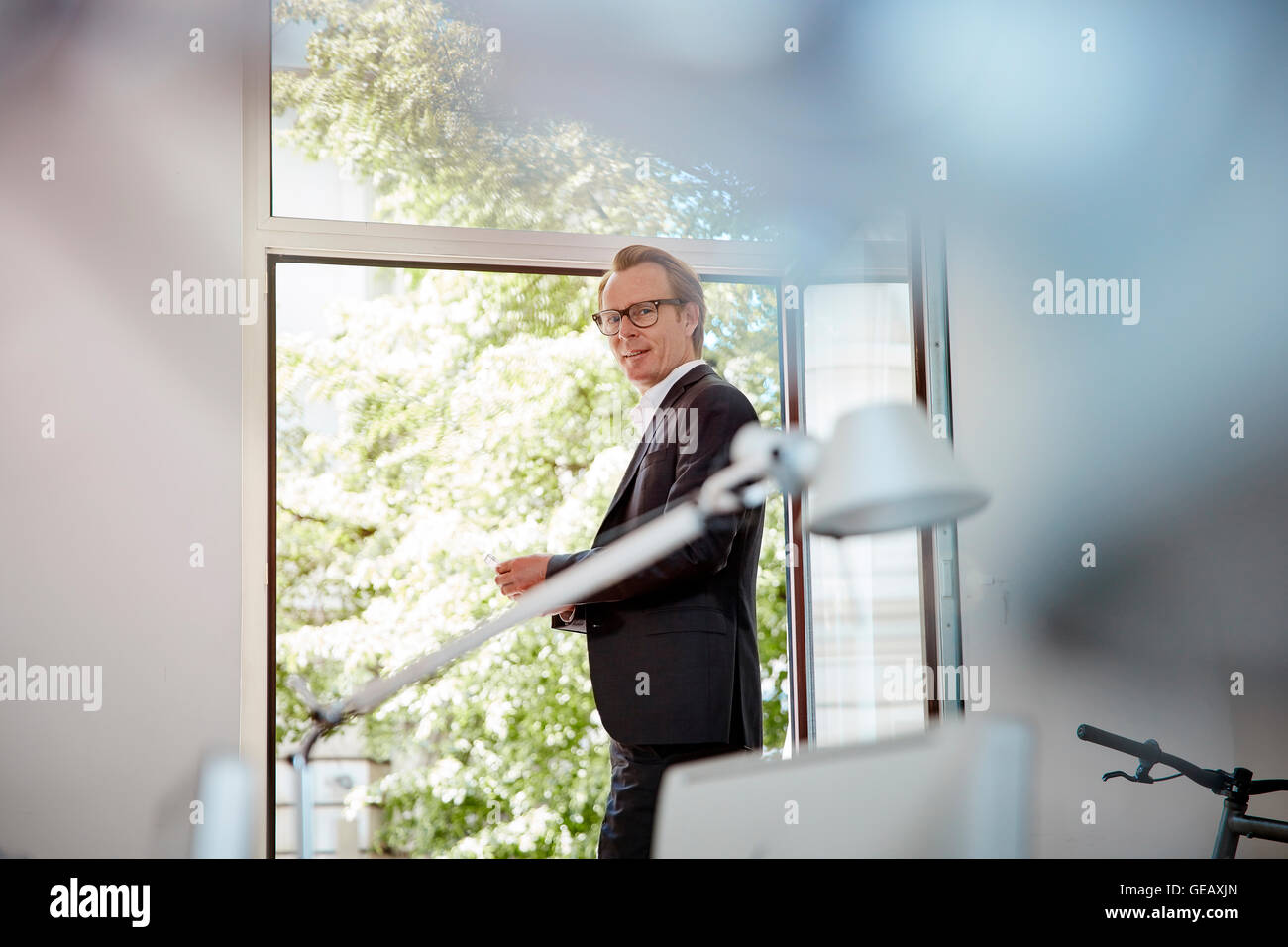 Smiling businessman standing in front of opened window Stock Photo - Alamy