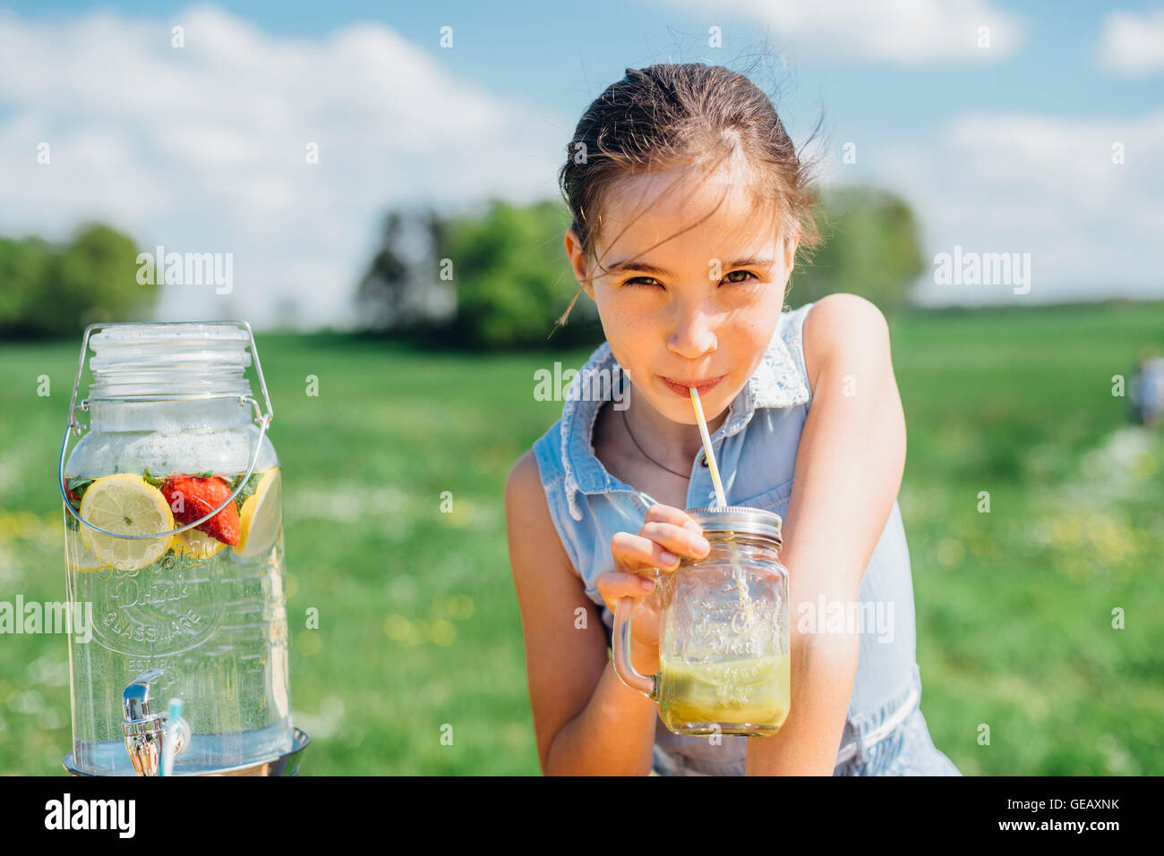 Girl outdoors drinking from jar Stock Photo - Alamy