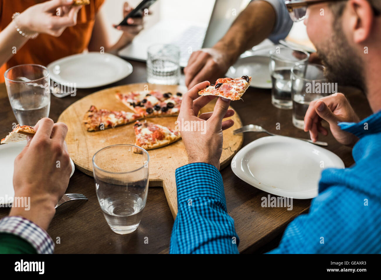Colleagues at table having a pizza Stock Photo - Alamy