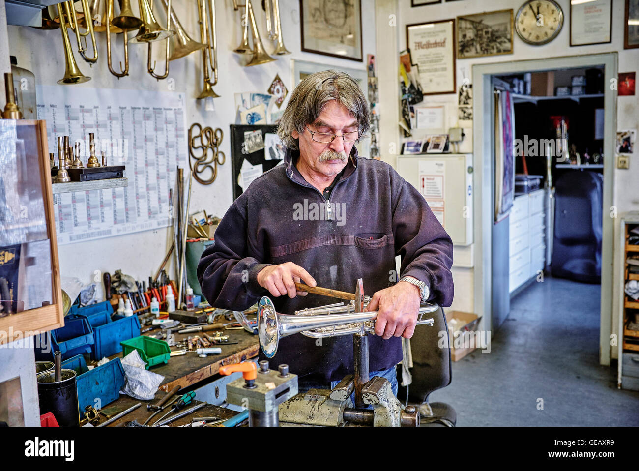 Instrument maker repairing trumpet in workshop Stock Photo - Alamy