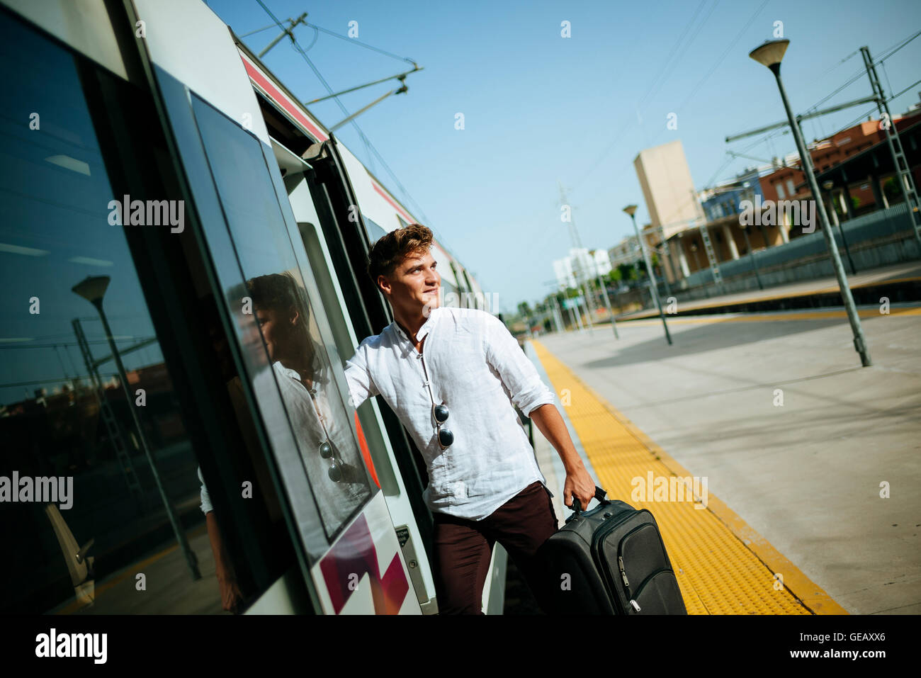 Young man with suitcase entering a train Stock Photo - Alamy