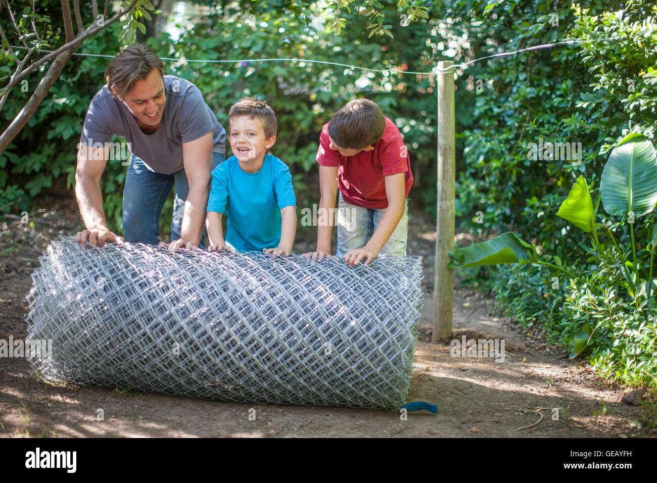 Father and sons building up a fence together Stock Photo - Alamy