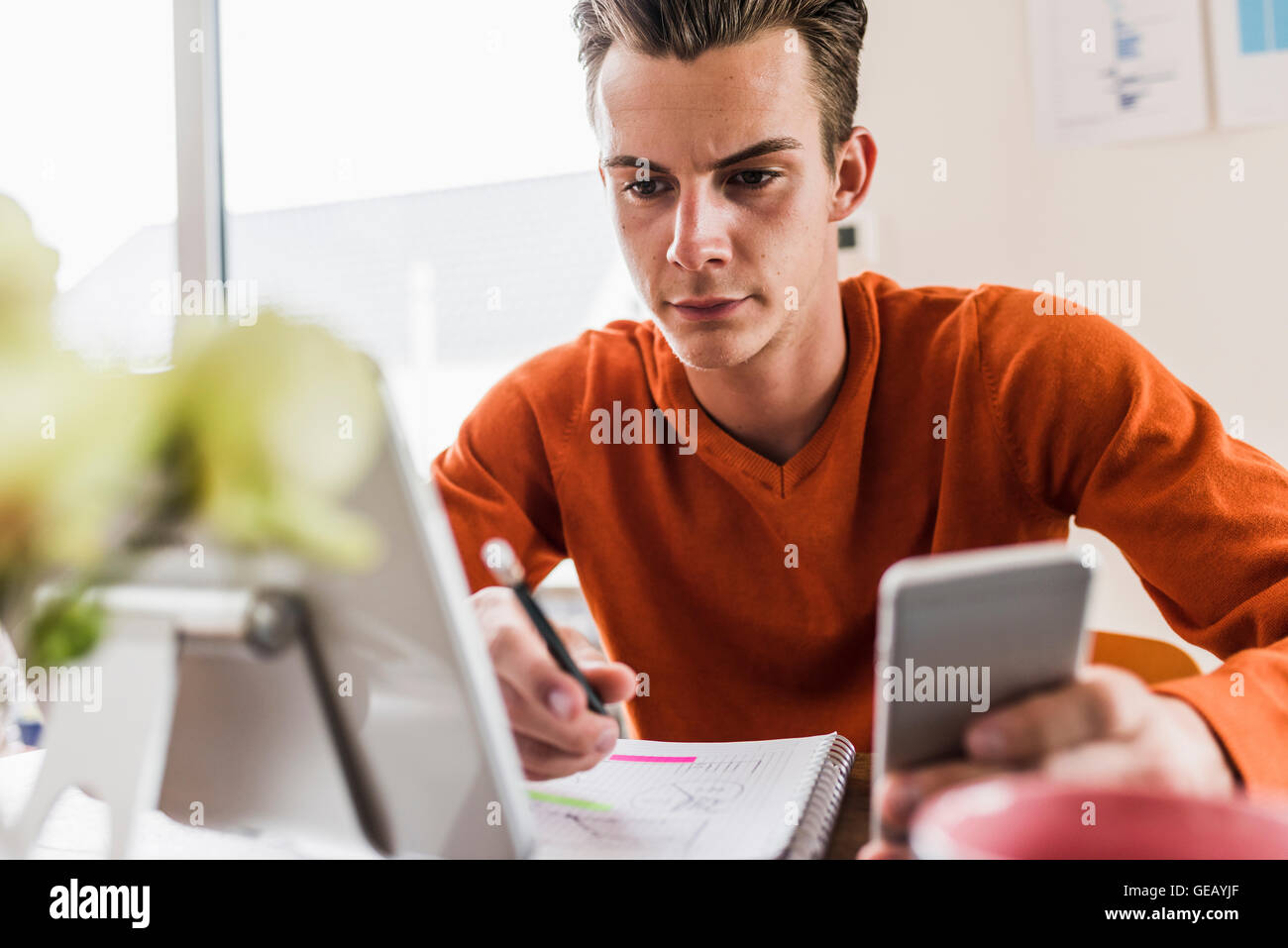 Man at desk with cell phone, digital tablet and notepad Stock Photo - Alamy