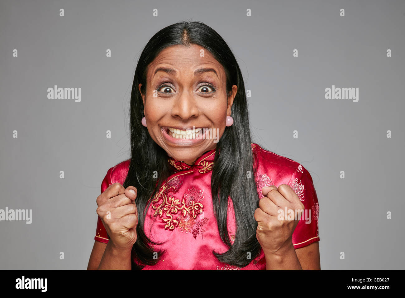 Portrait of woman pulling funny faces while keeping fingers crossed ...