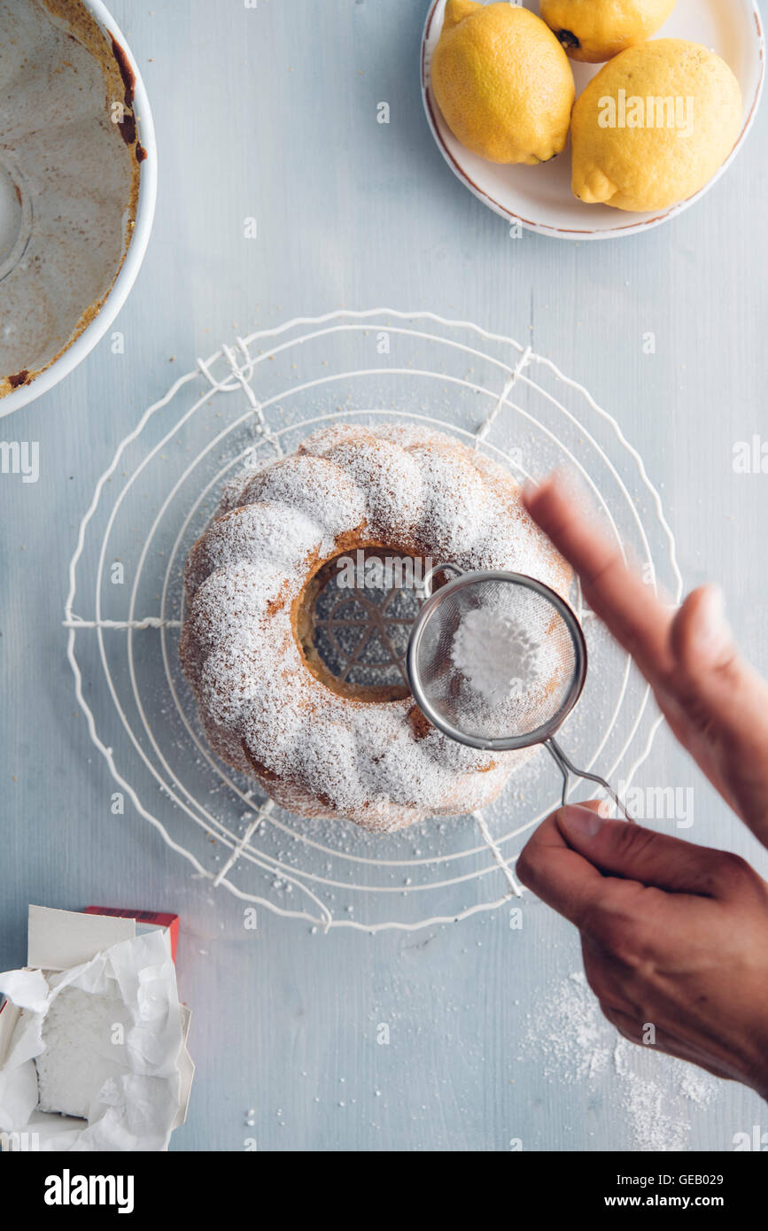 Woman's hands sprinkling icing sugar on ring cake Stock Photo - Alamy