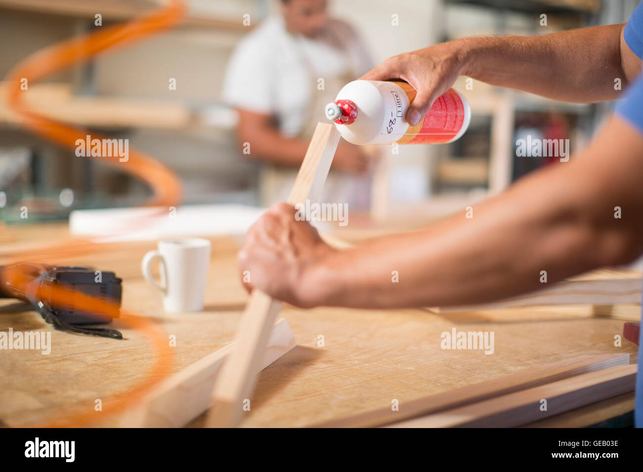 Man putting glue on frame in canvas workshop Stock Photo - Alamy