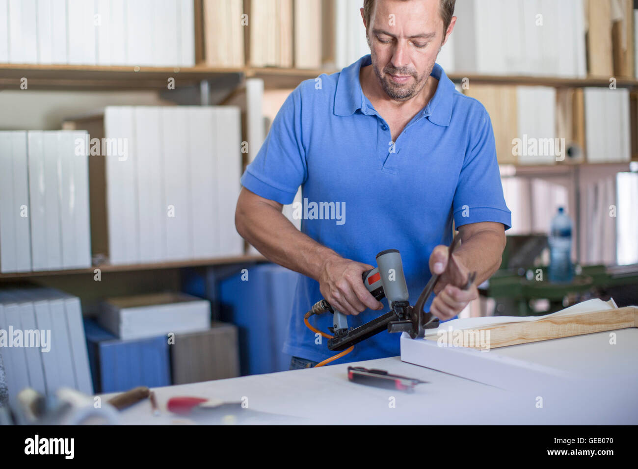 Man working on frame in canvas workshop Stock Photo - Alamy