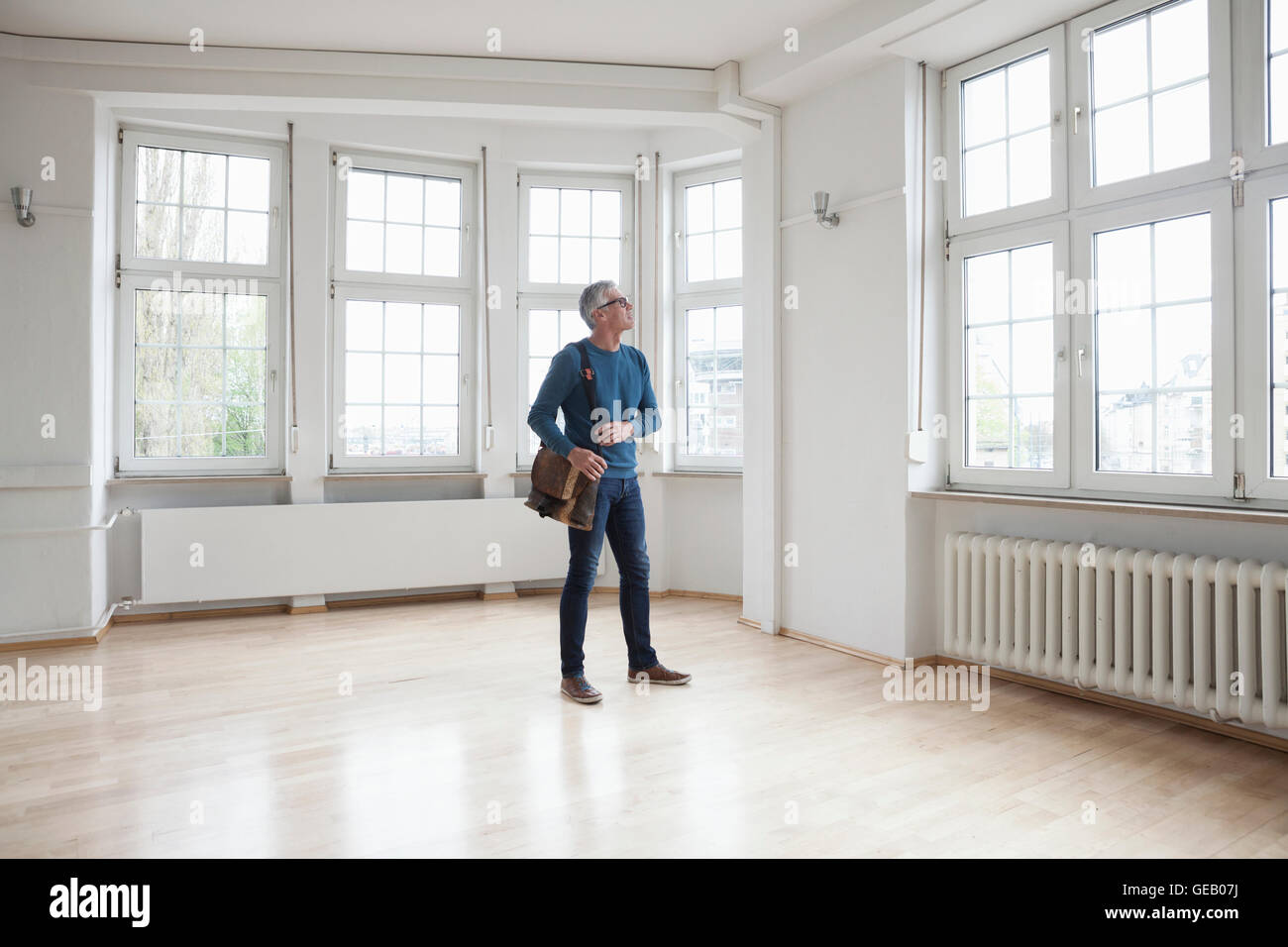 Man looking around in empty apartment Stock Photo - Alamy