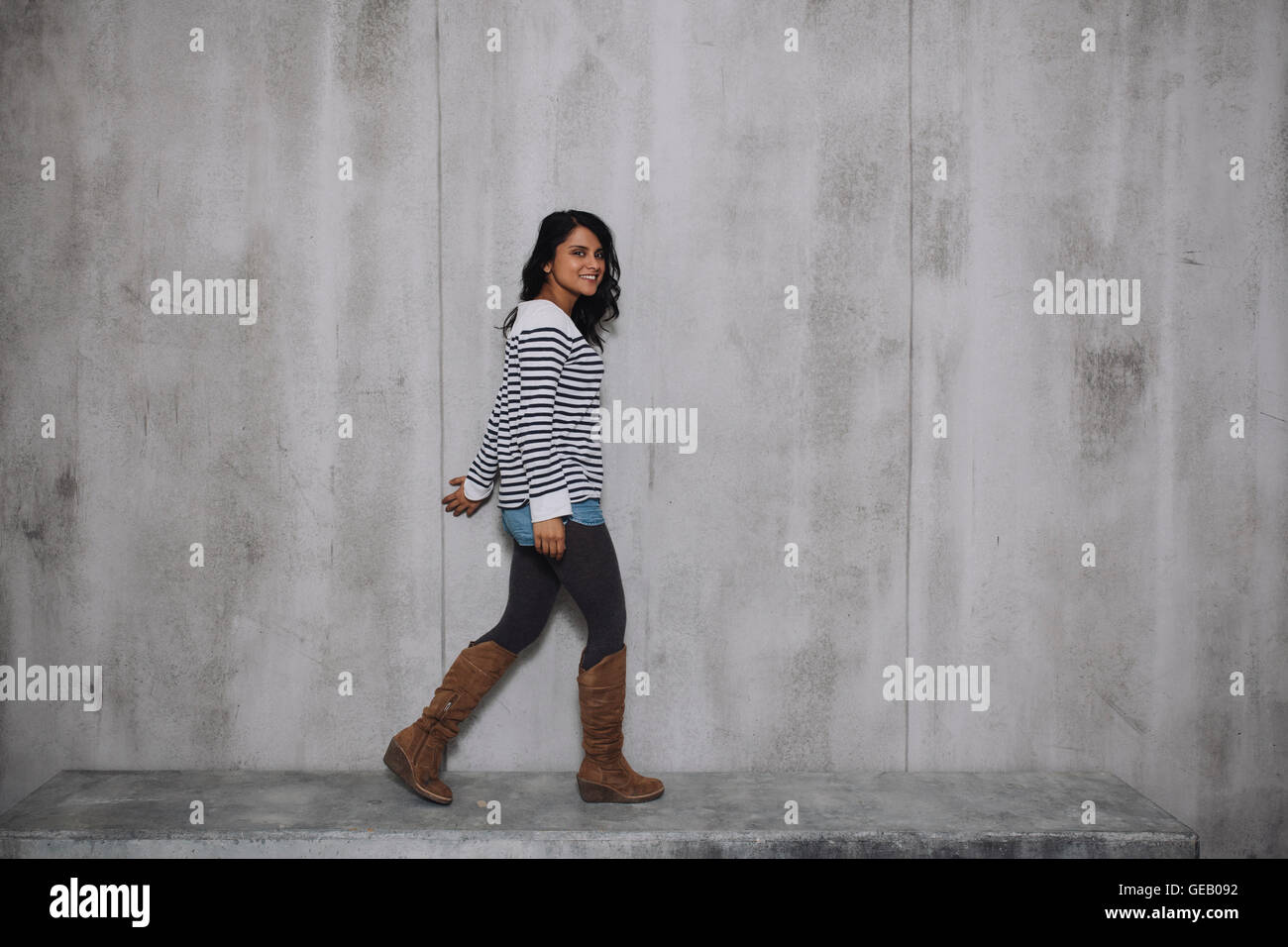 Female Indian walking in front of gray wall Stock Photo - Alamy