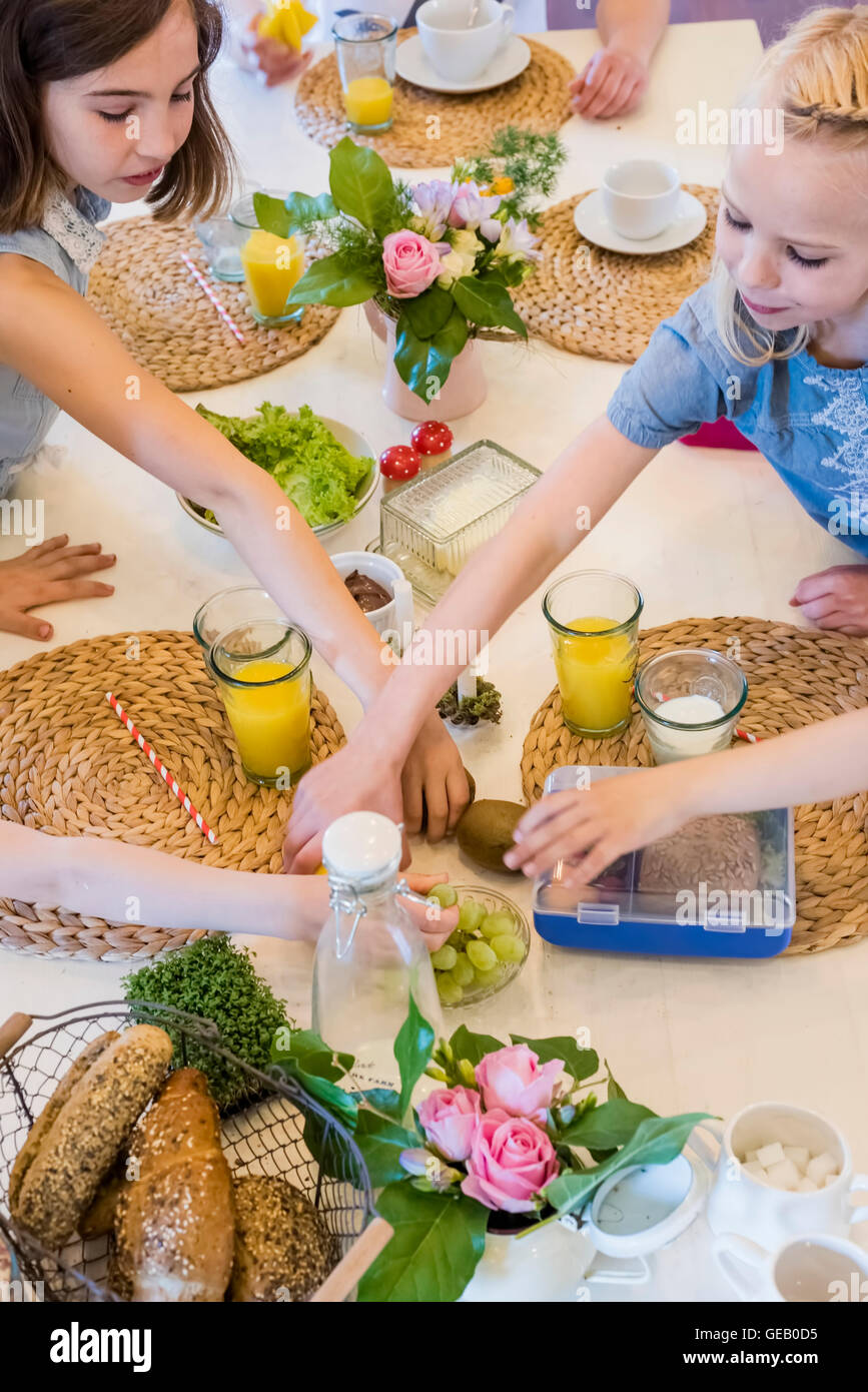 Girls reaching for food on laid table Stock Photo - Alamy