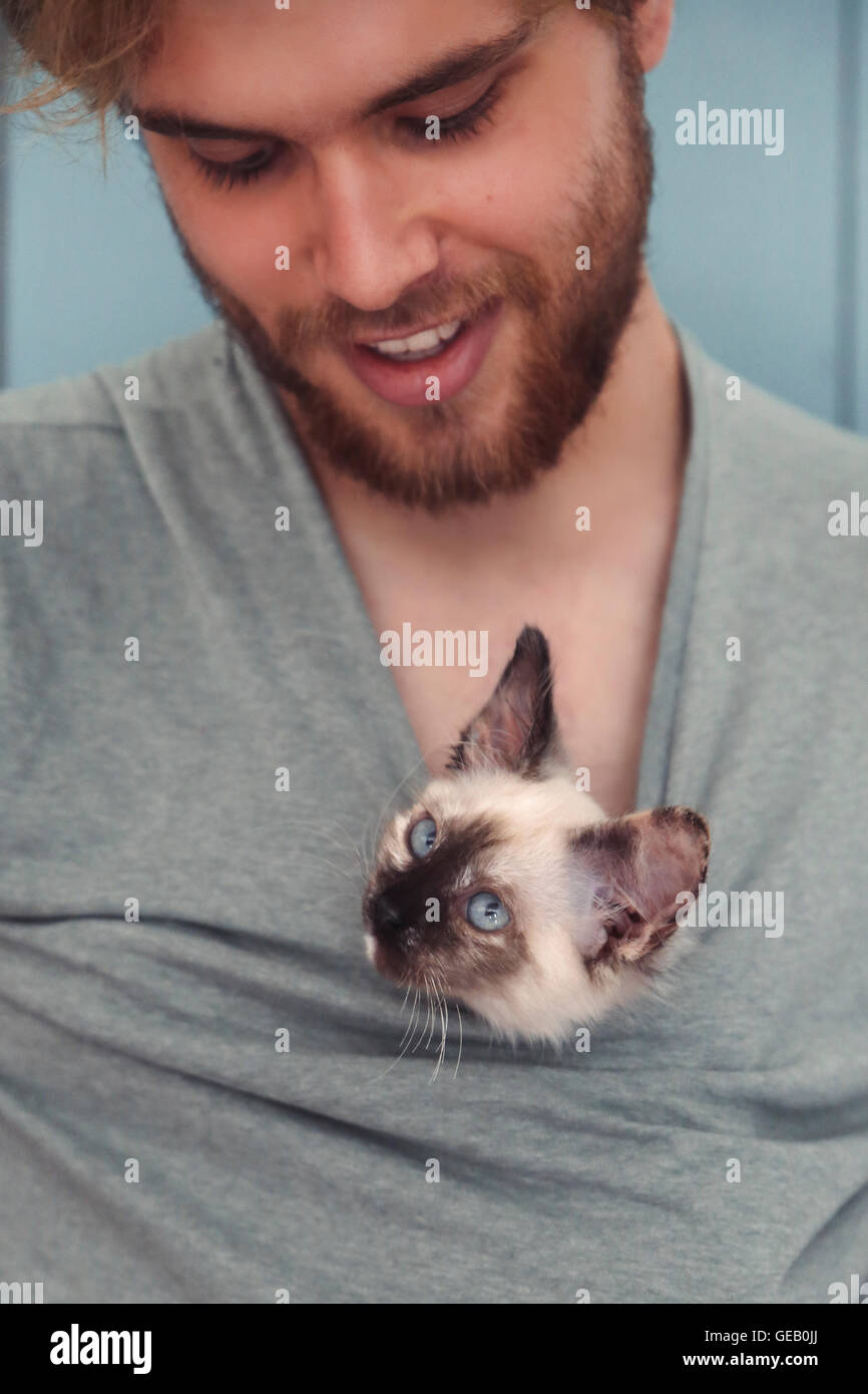 Portrait of young man with kitten inside his shirt Stock Photo - Alamy