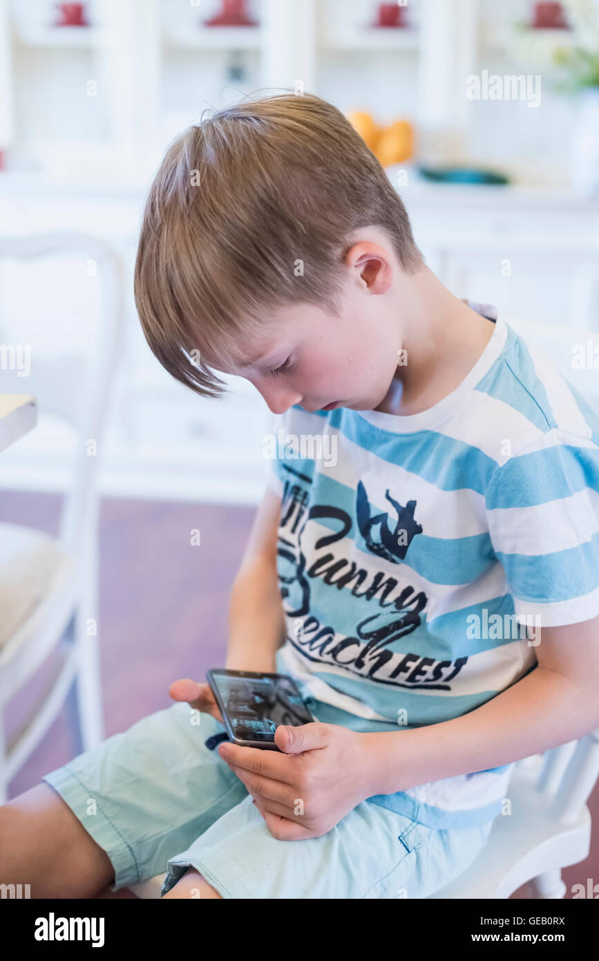 Boy sitting looking at cell phone Stock Photo - Alamy