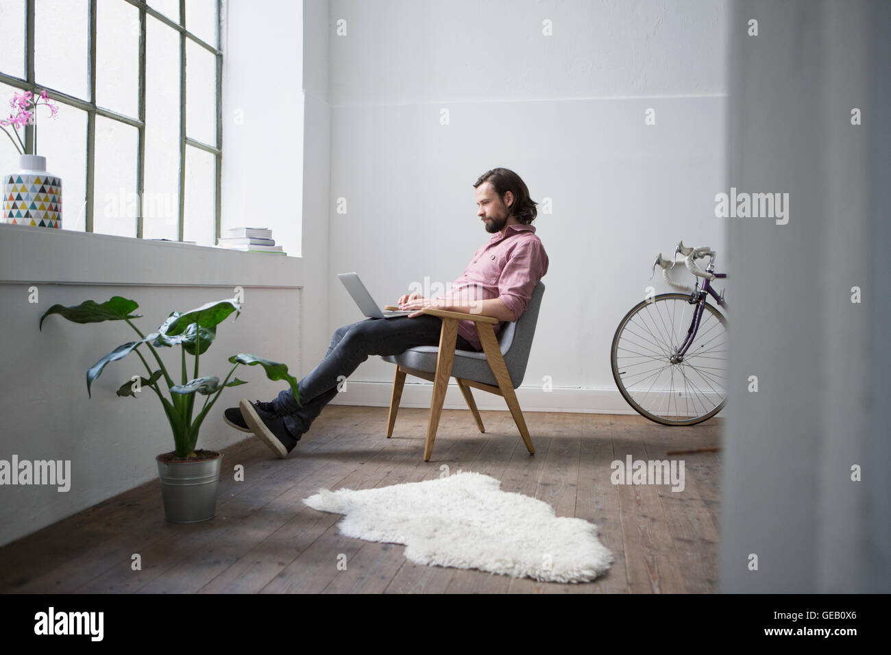 Man sitting in chair using laptop Stock Photo - Alamy
