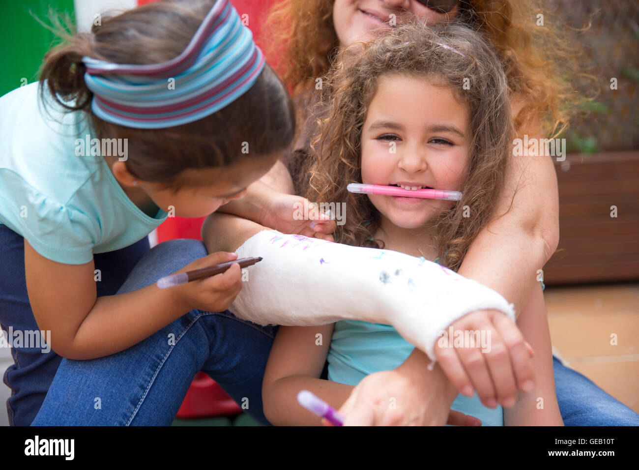 Little girls painting her mother's plaster arm Stock Photo - Alamy