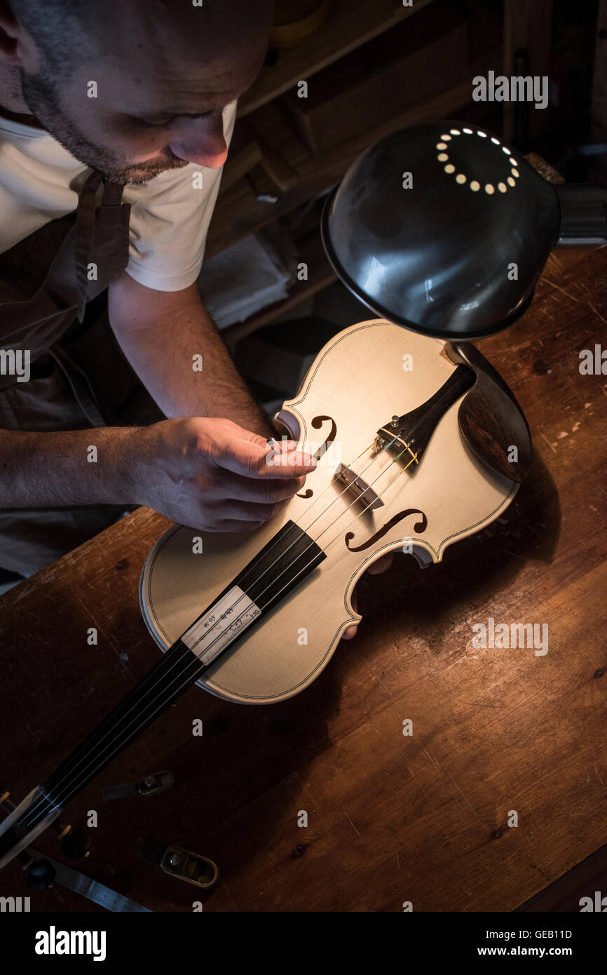 Luthier examining the sound post of an unvarnished violin in his ...