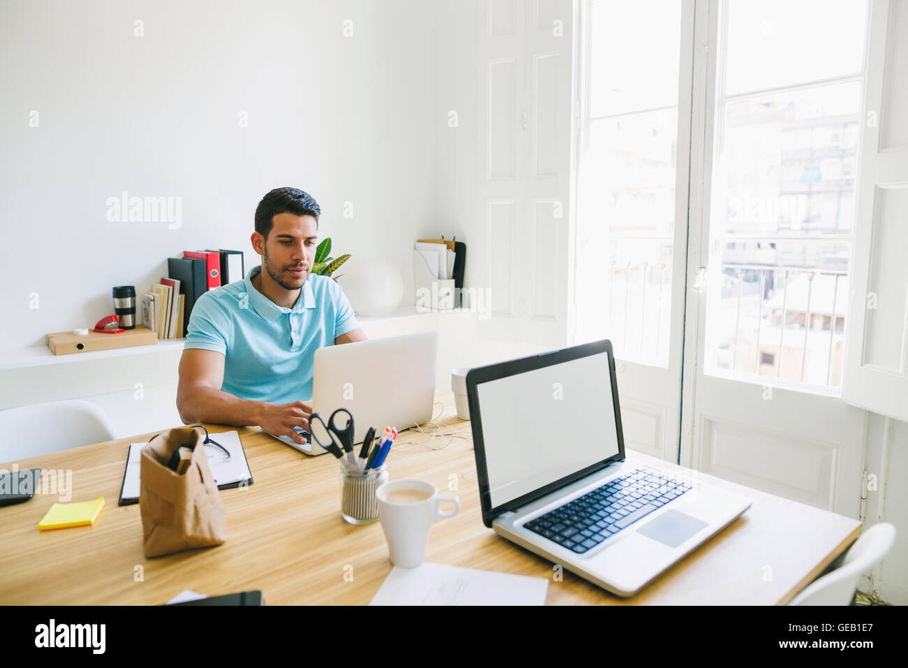 Young man working in office, using laptop Stock Photo - Alamy