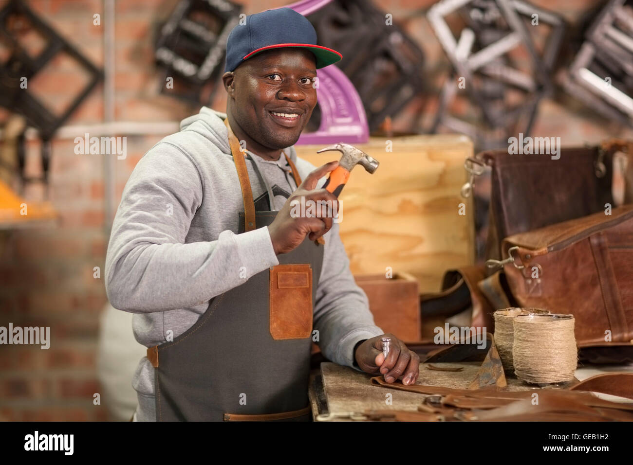 Portrait of smiling man working with hammer in leather workshop Stock ...