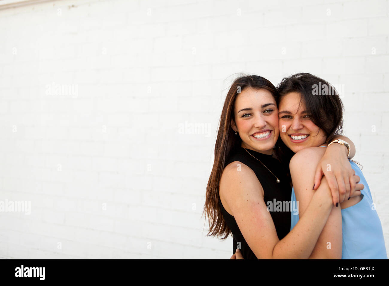 Two best friends hugging each other in front of white wall Stock Photo ...