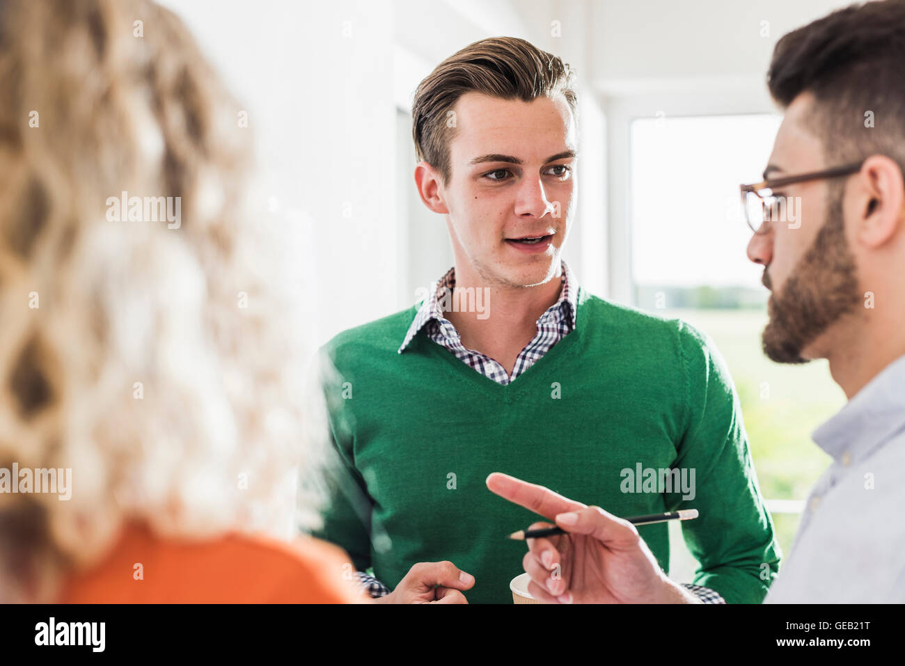 Three young professionals talking in office Stock Photo - Alamy