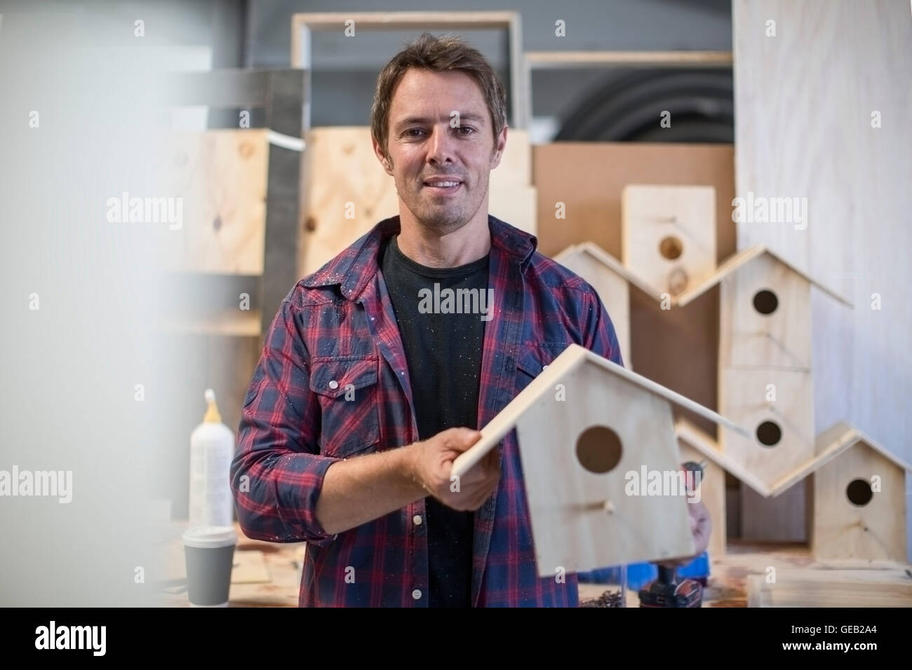 Smiling man holding self-made birdhouse in workshop Stock Photo - Alamy