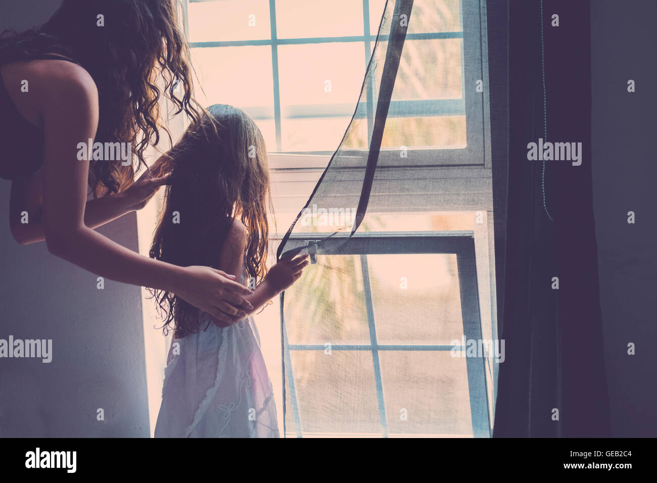 Teenage girl and her little sister looking through window Stock Photo ...