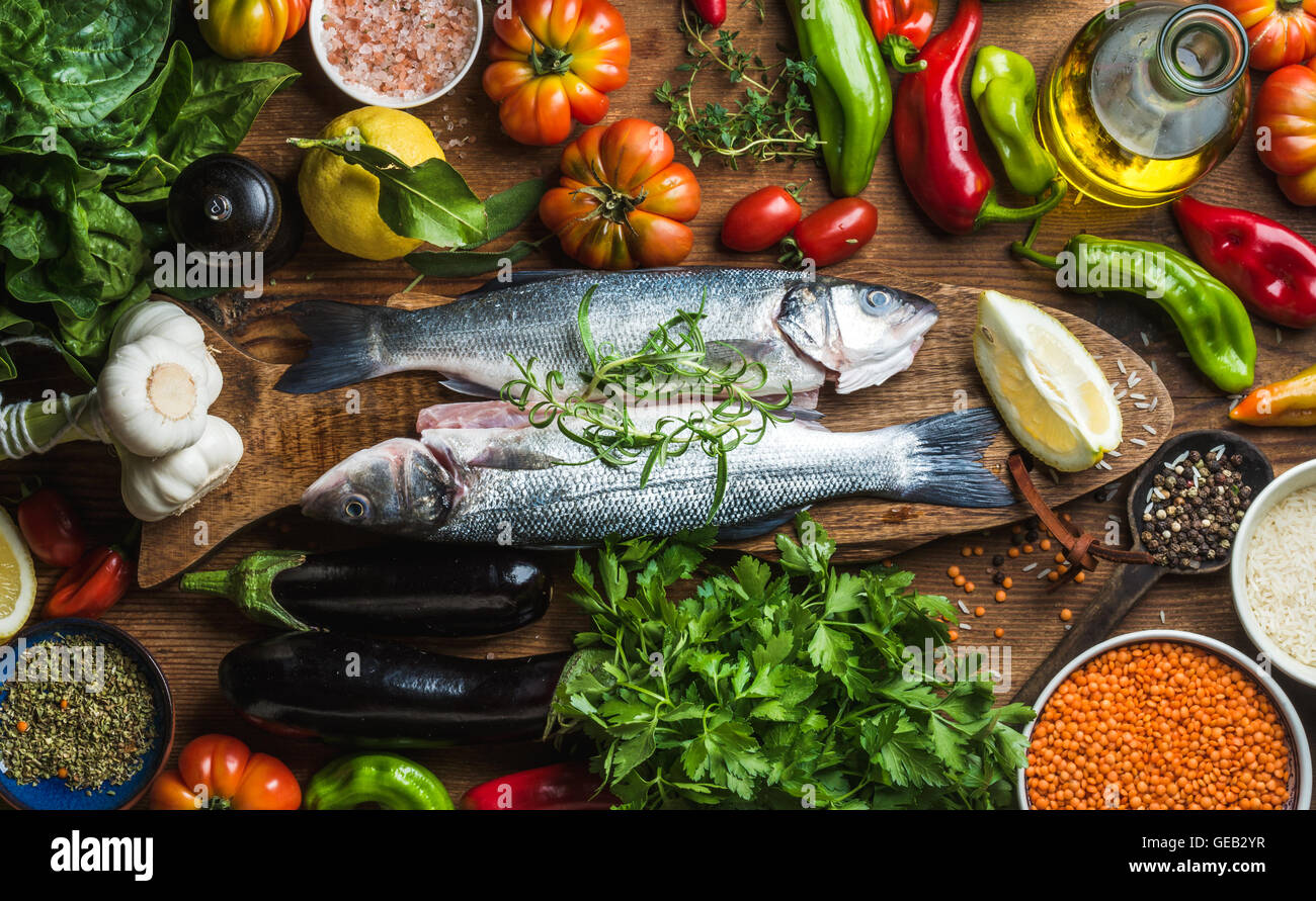Raw uncooked seabass fish with vegetables, grains, herbs and spices on ...