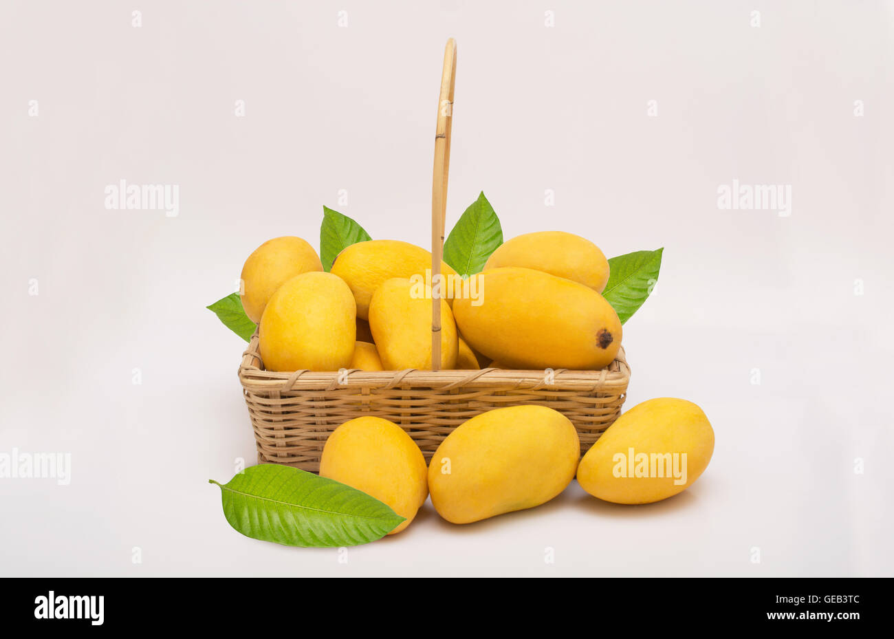 Fresh ripe chaunsa mangoes with green leaf and basket on white Stock ...