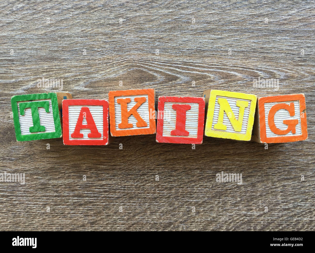 Alphabet wood block letters forming the verb TAKING , combining those ...