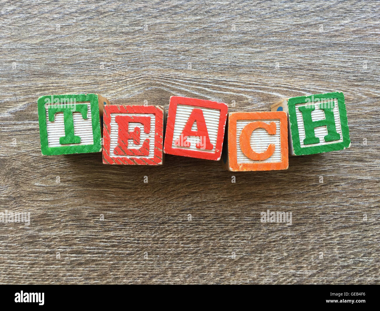 Alphabet wood block letters forming the verb TEACH, combining those ...