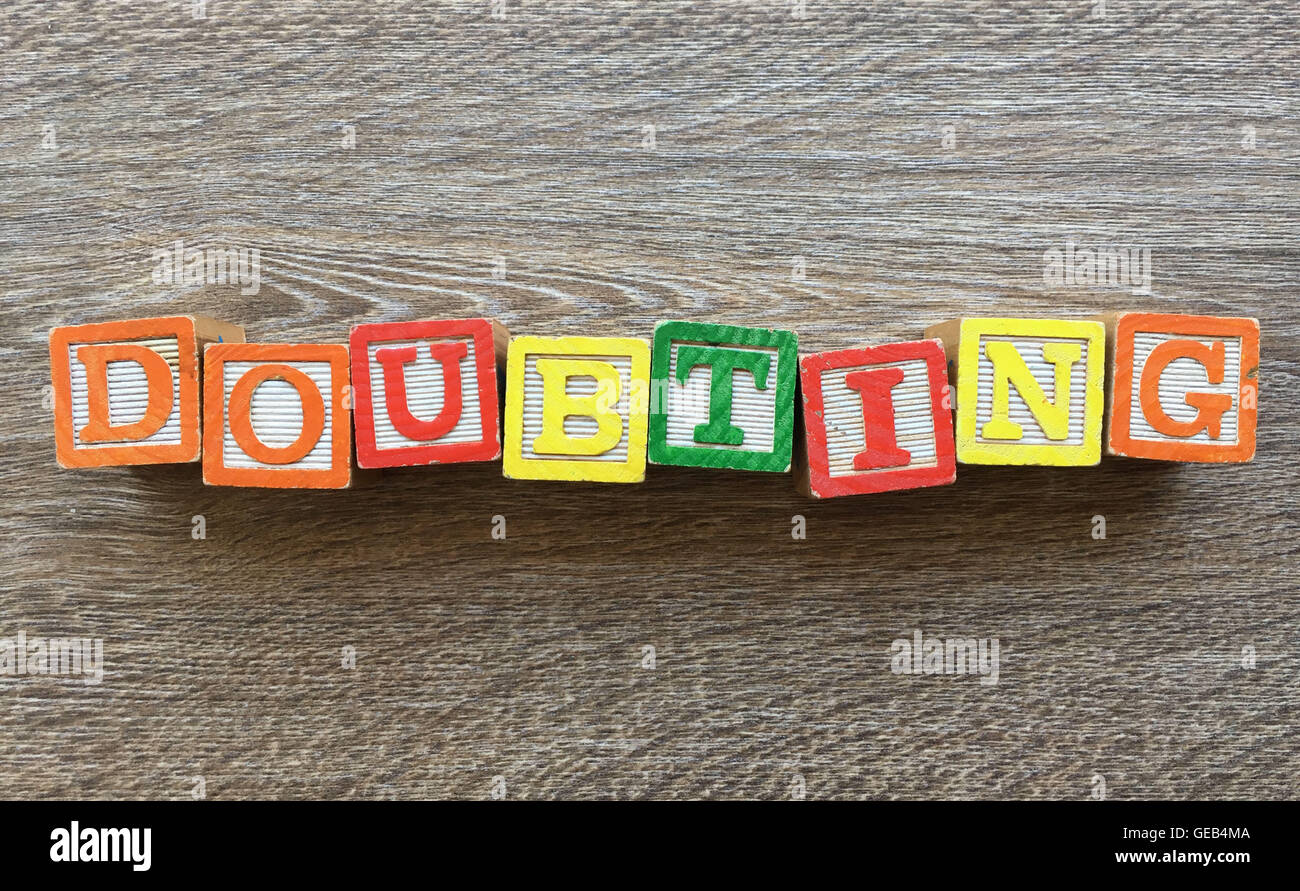 Alphabet wood block letters forming the verb DOUBTING, combining those ...