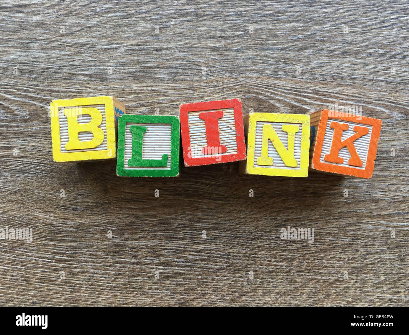 Alphabet wood block letters forming the verb BLINK, it is a way for ...