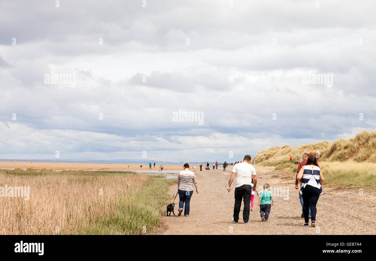 Family of holiday makers walking along Presthaven beach resort in ...