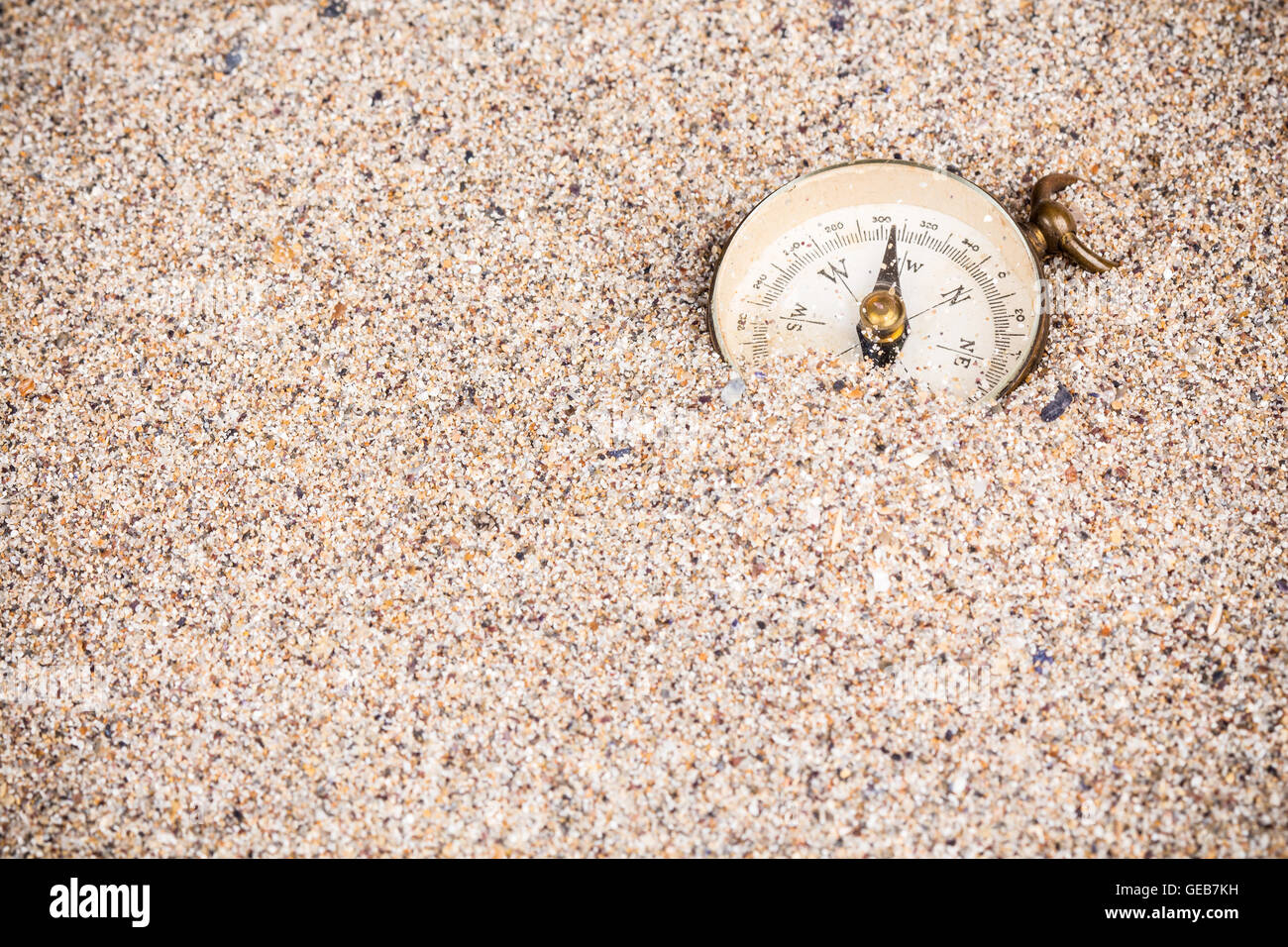 Adventure background with compass disappearing in sand Stock Photo - Alamy