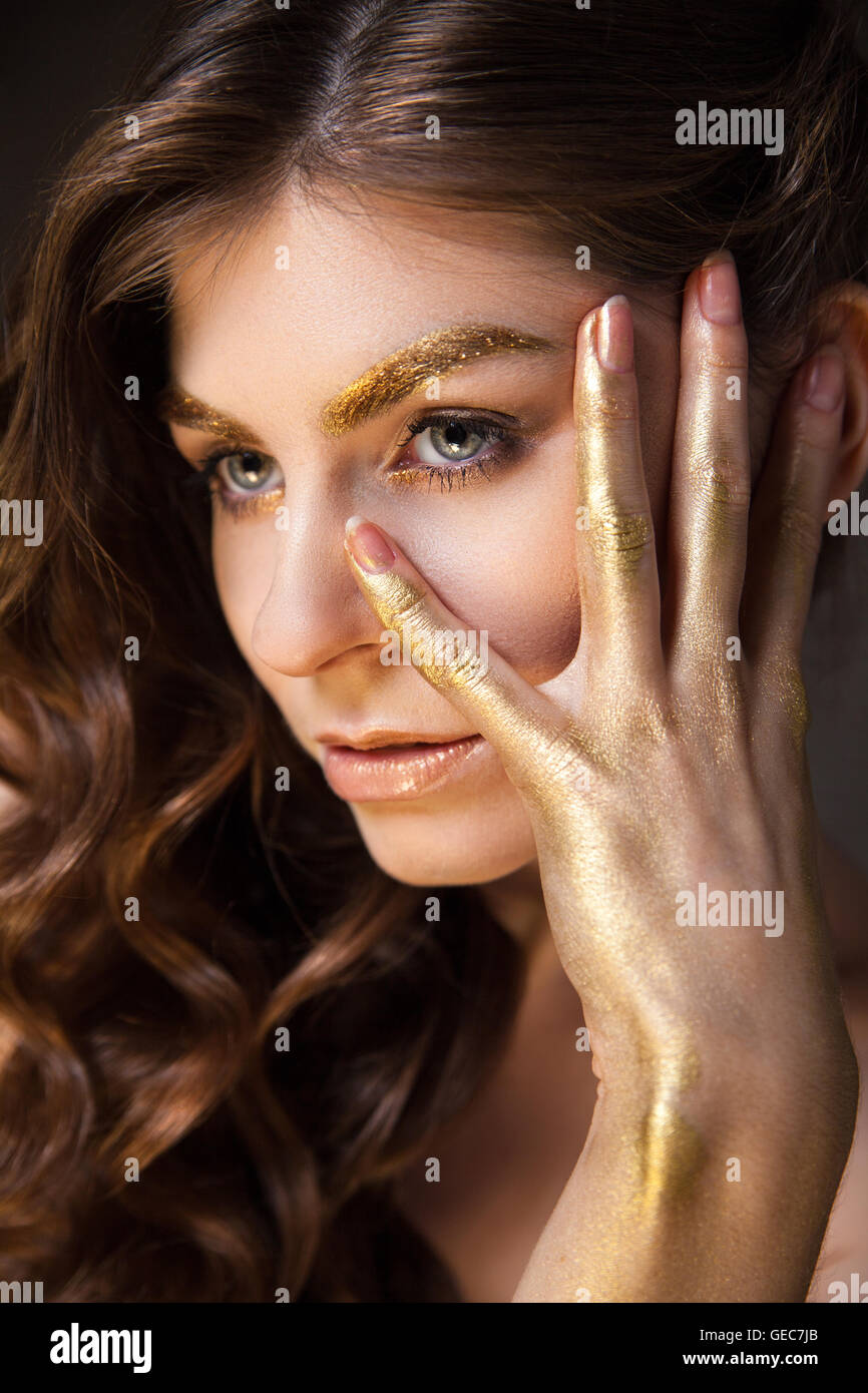 Young model with fashion make up and hand covered in gold Stock Photo ...