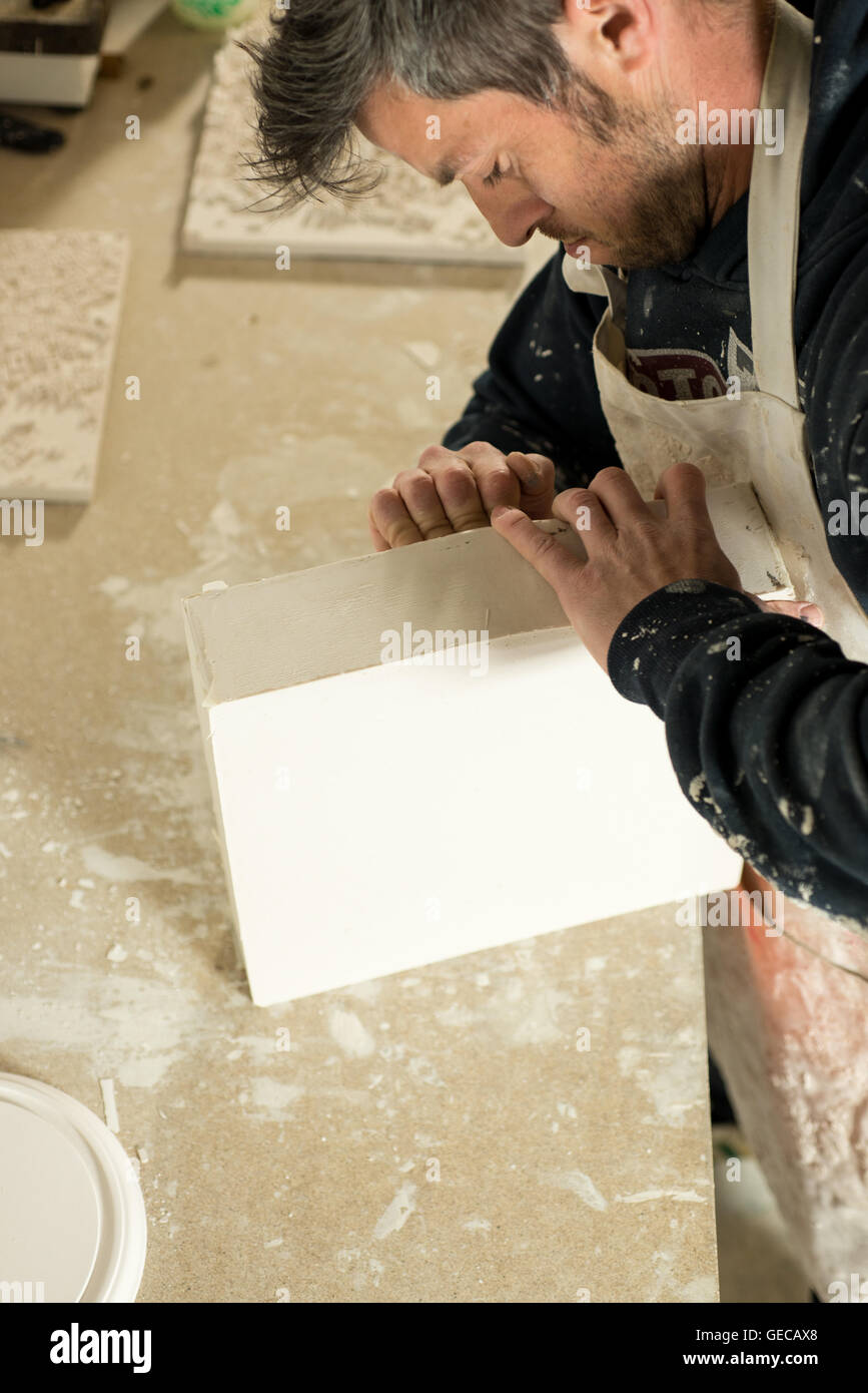 A man trying to detach a plaster model from mold using bare hands Stock ...