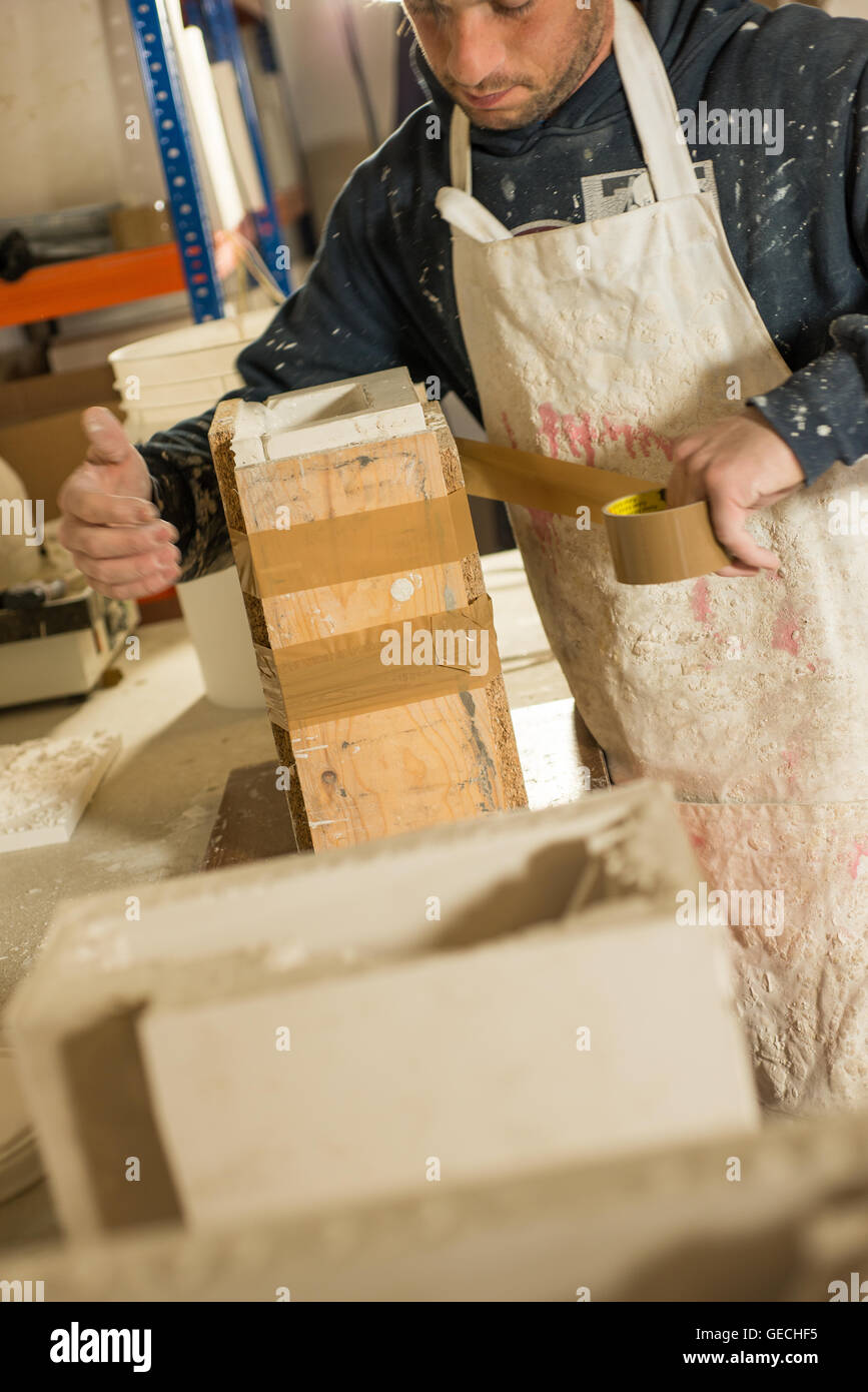 A man in plaster-splattered clothing assembling and sealing a plaster ...