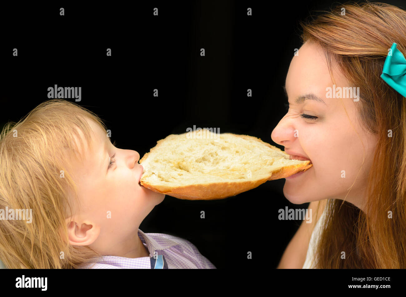 Mother playing with her child biting from the same piece of bread Stock ...