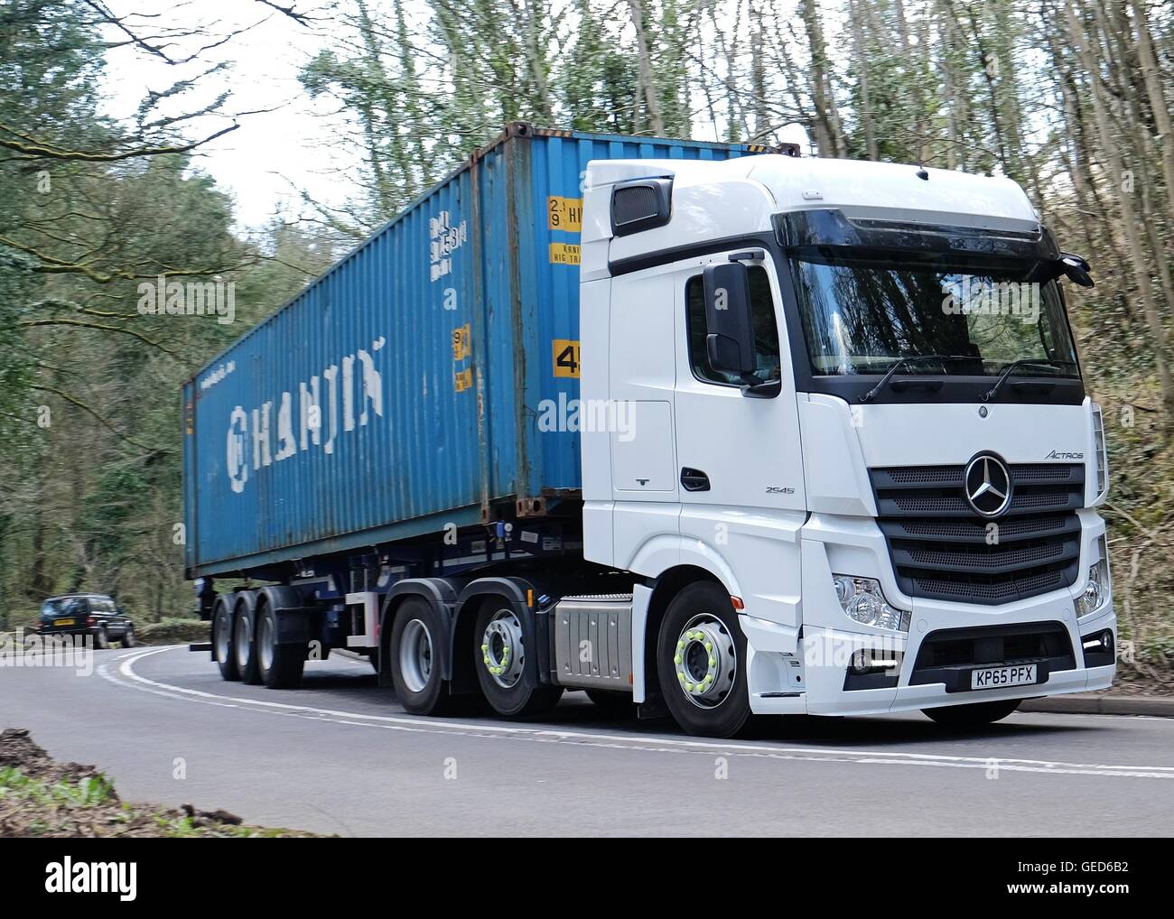 Mercedes Actros tractor unit pulling shipping container rounding a bend ...