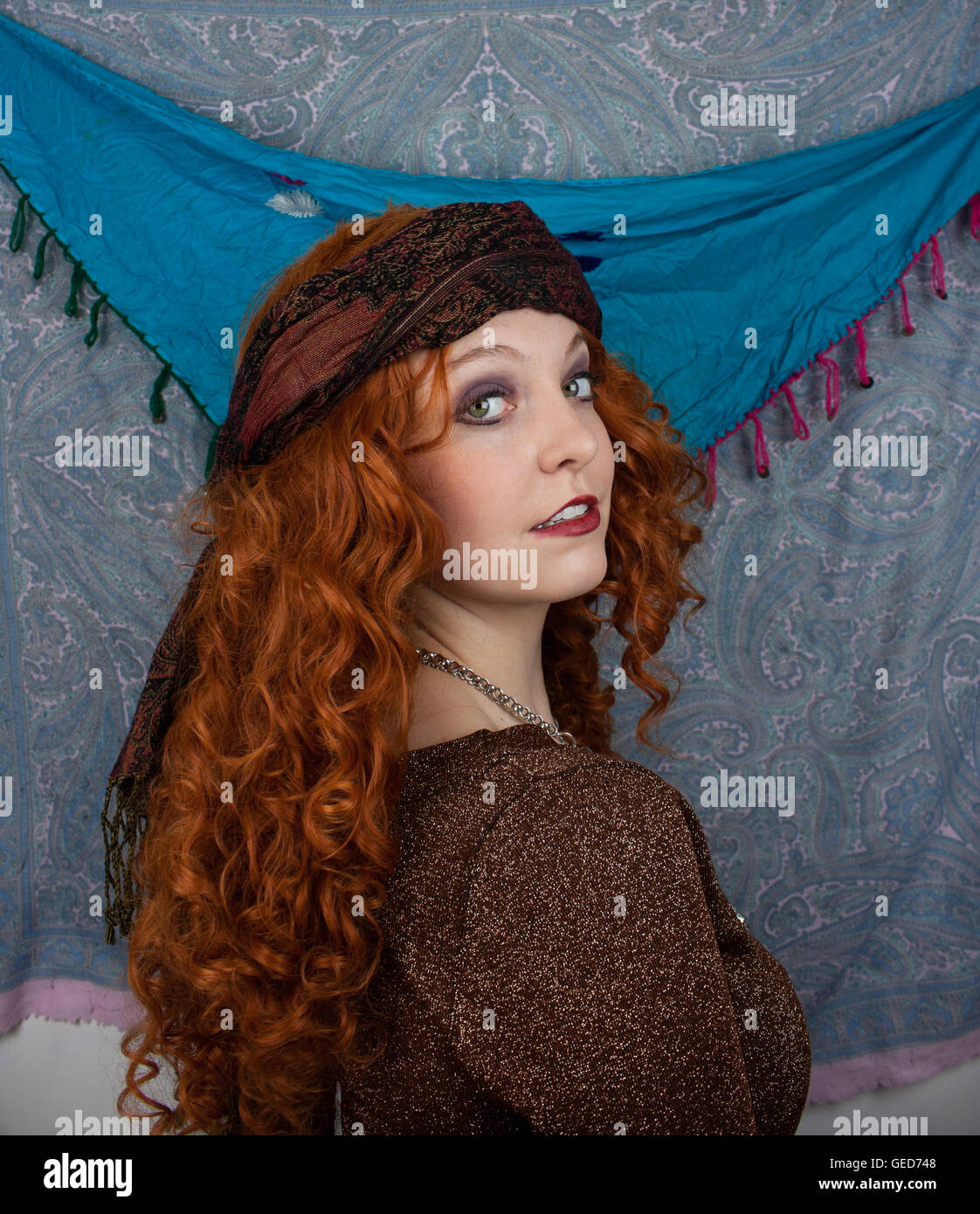 Beautifiul young woman with long curly red hair dressed as a gypsy ...