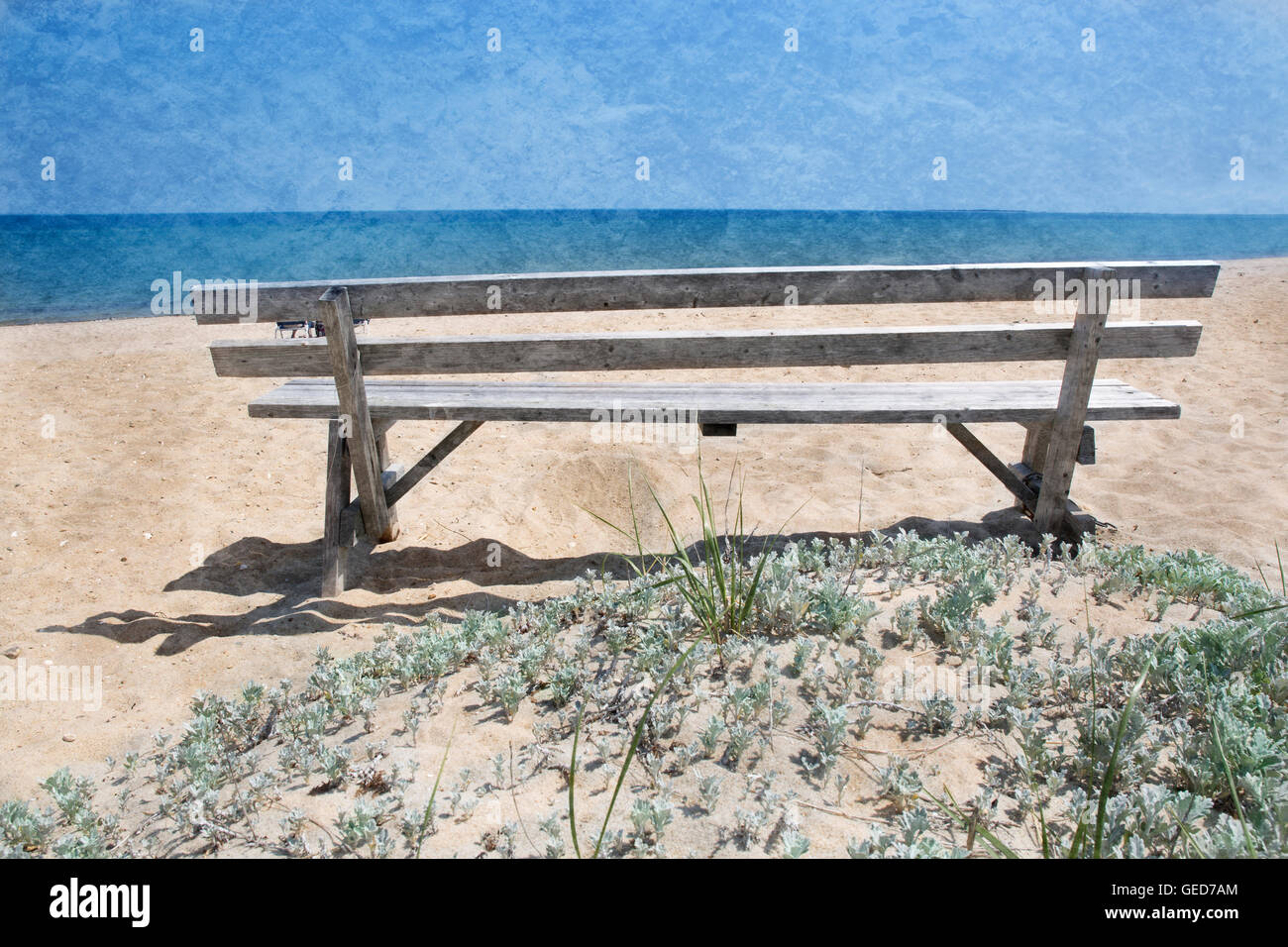 Bench on a beach on Martha's Vineyard with blue sky, sand and water ...