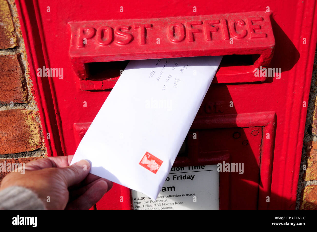 Posting letter in Royal Mail wall pillar box, Stanwell Moor, Surrey ...