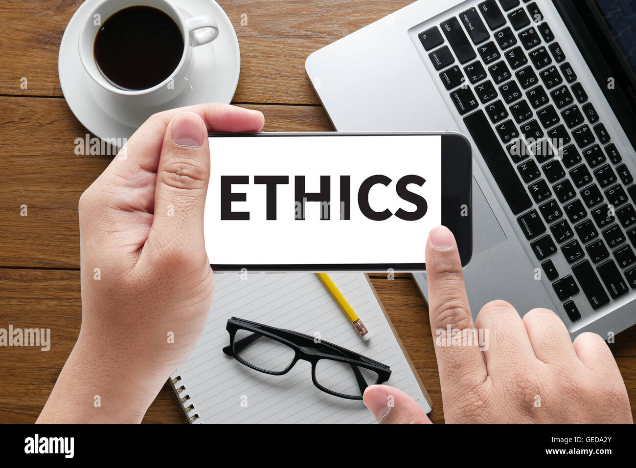 ETHICS message on hand holding to touch a phone, top view, table ...