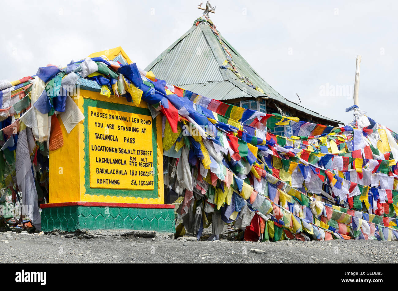 Sign and prayer flags beside dirt road over mountain pass, Tanglangla ...