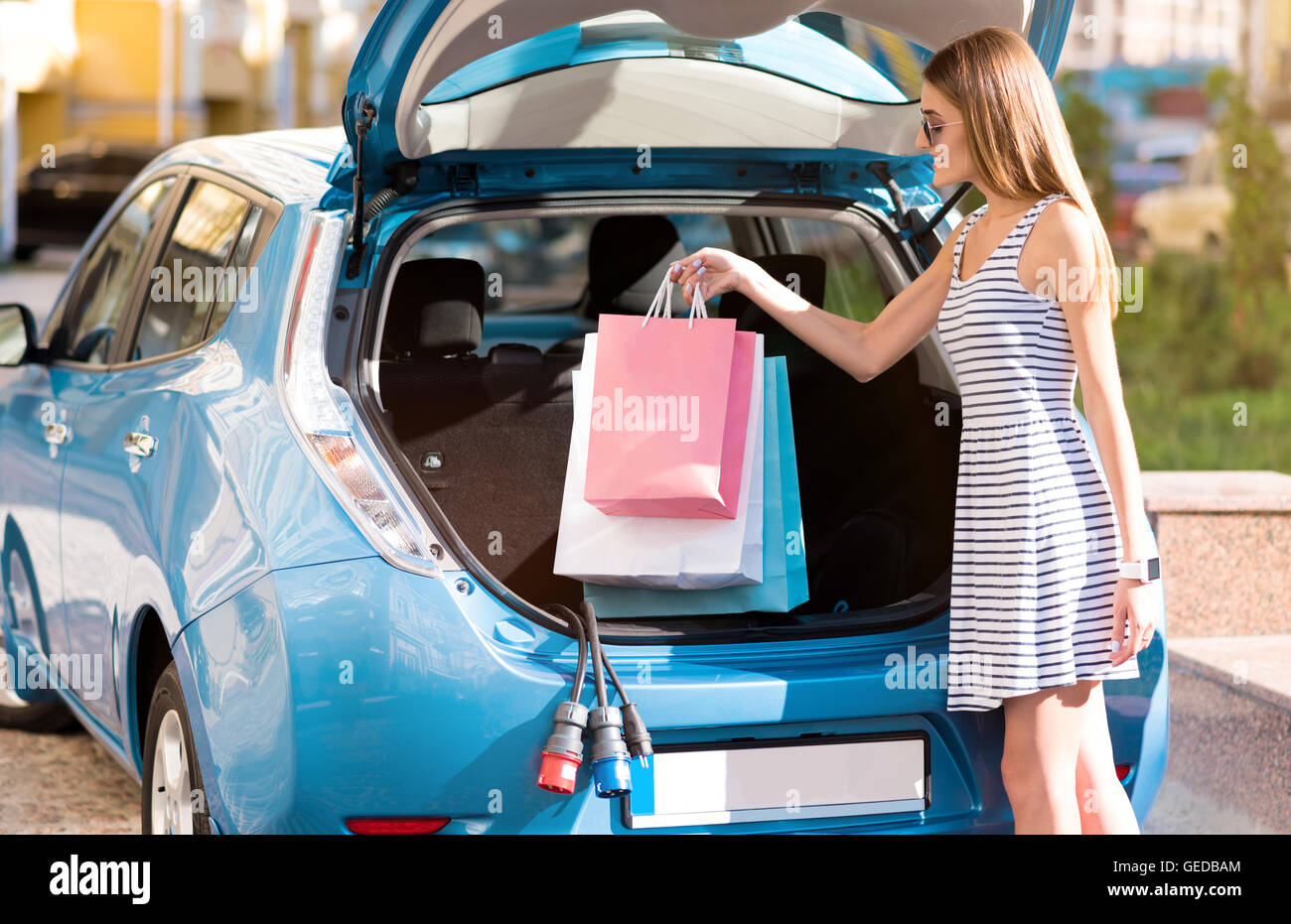 Woman putting purchases into trunk Stock Photo - Alamy