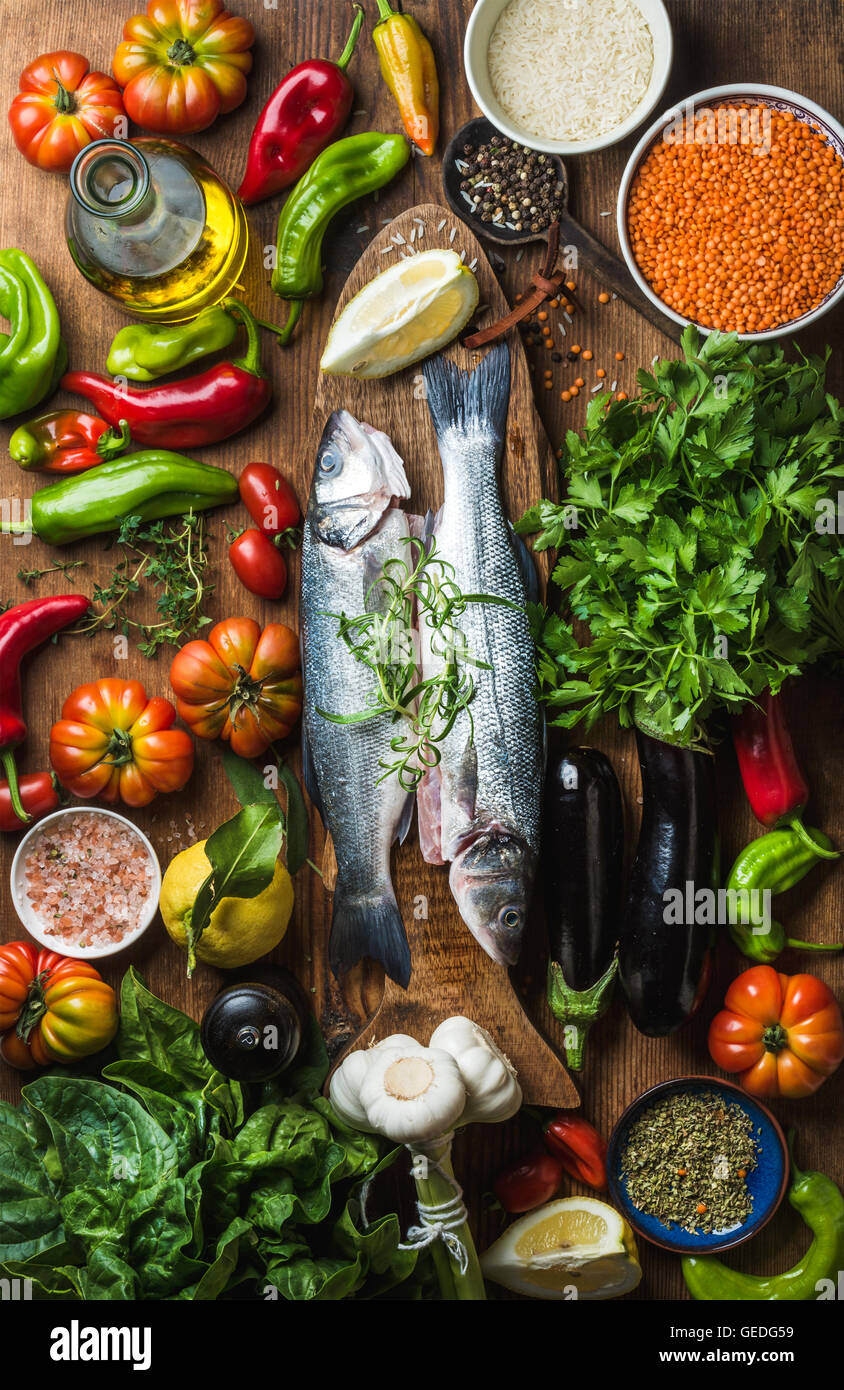 Raw uncooked seabass fish, vegetables, grains, herbs, rice spices and ...