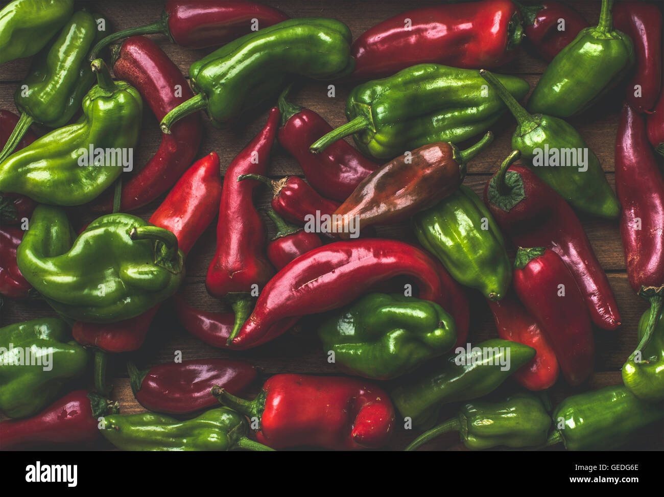 Background of colorful red and green bell peppers over wooden backdrop ...