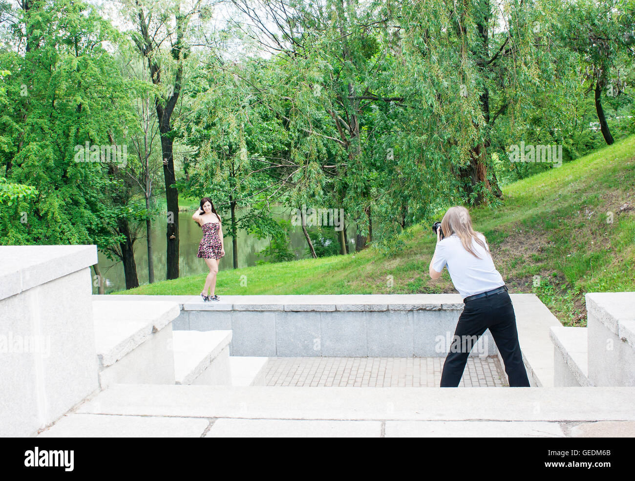 photographer takes a young woman standing on the stairs in the park on ...
