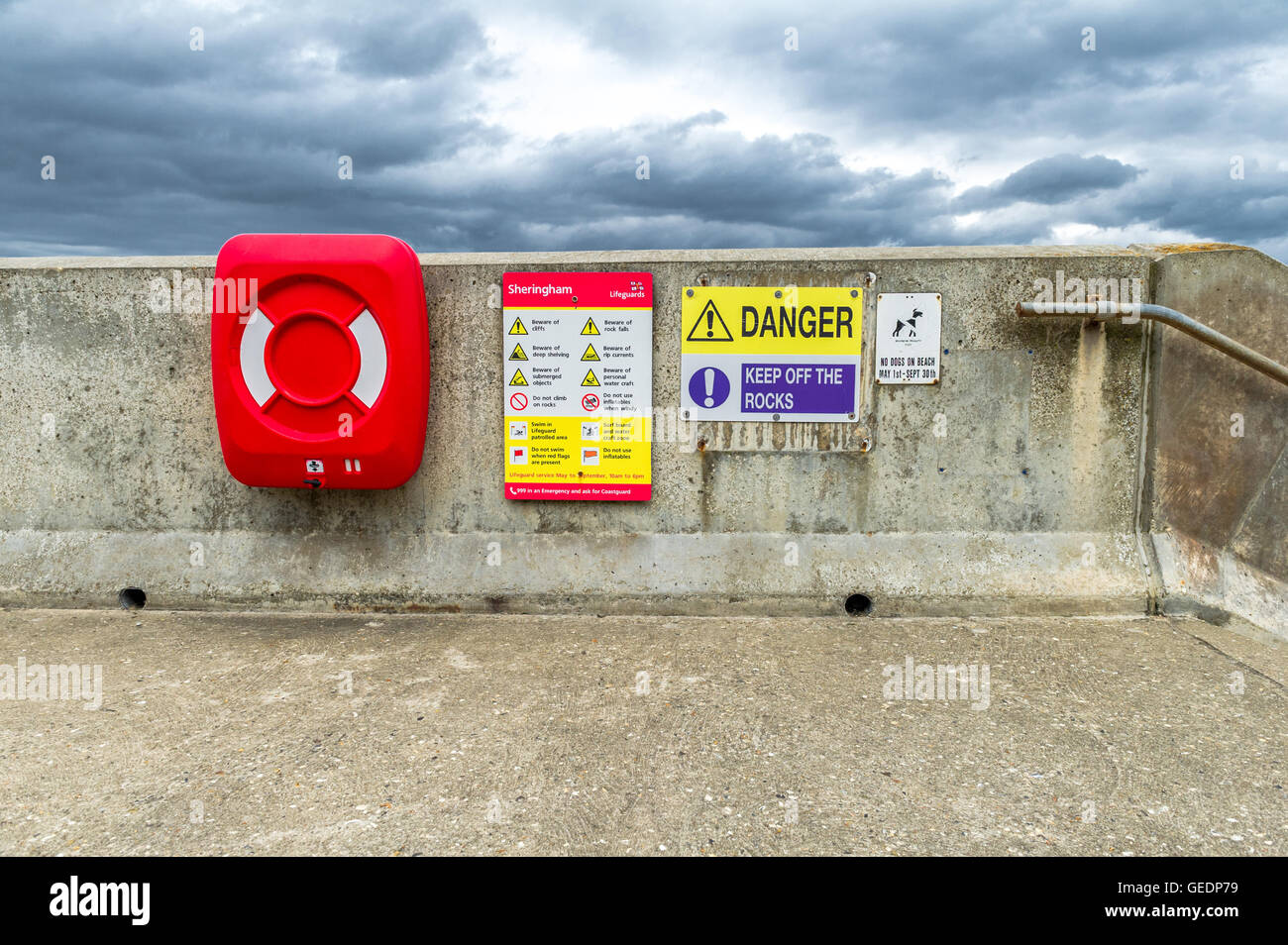 Warning signs, notices and lifebuoy mounted onto a concrete sea wall at ...